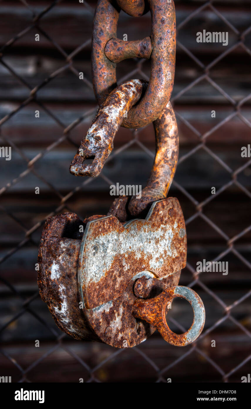 Big old rusty metal open padlock with a key hanging on a bold chain ...