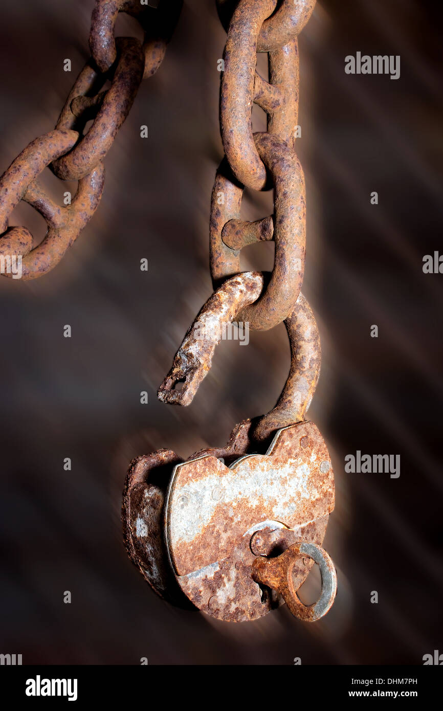 Big old rusty metal open padlock with a key hanging on a bold chain ...