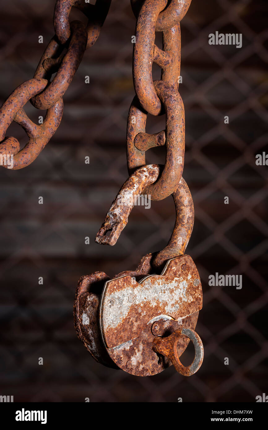 Big old rusty metal open padlock with a key hanging on a bold chain ...