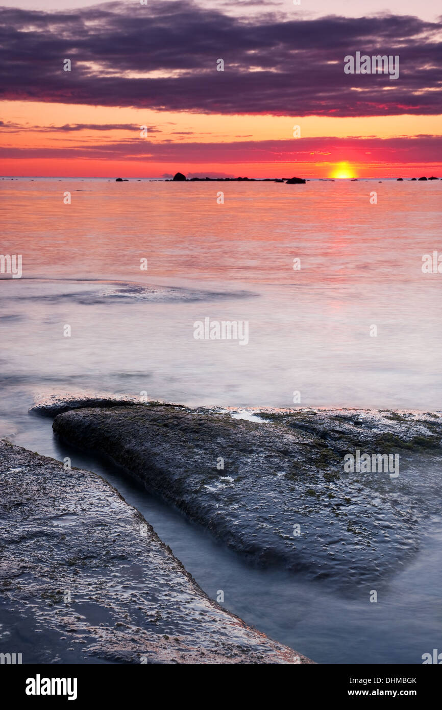 Beautiful colorful sunset at sea. Large rocks in water in foreground ...