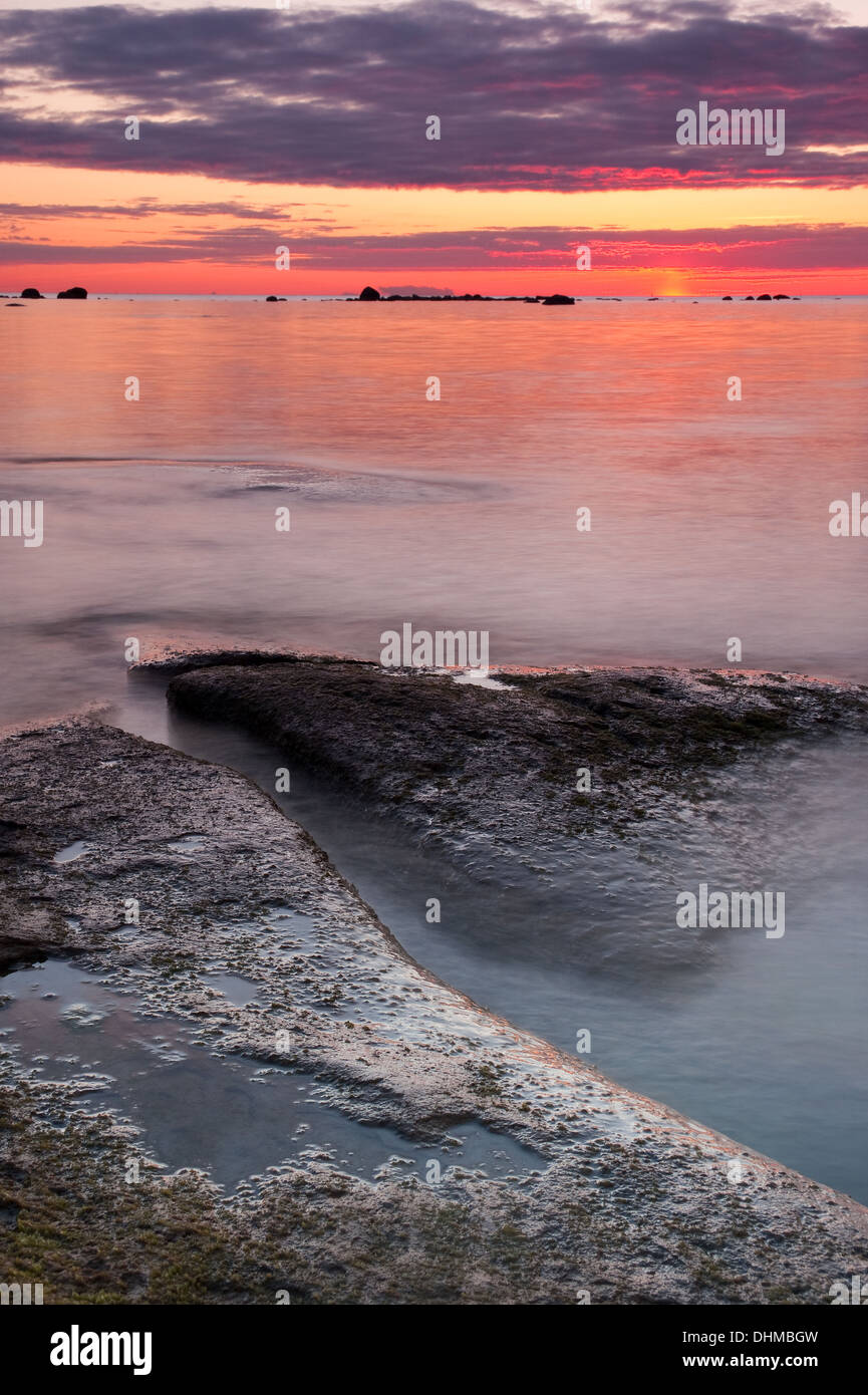 Beautiful colorful sunset at sea. Large rocks in water in foreground ...