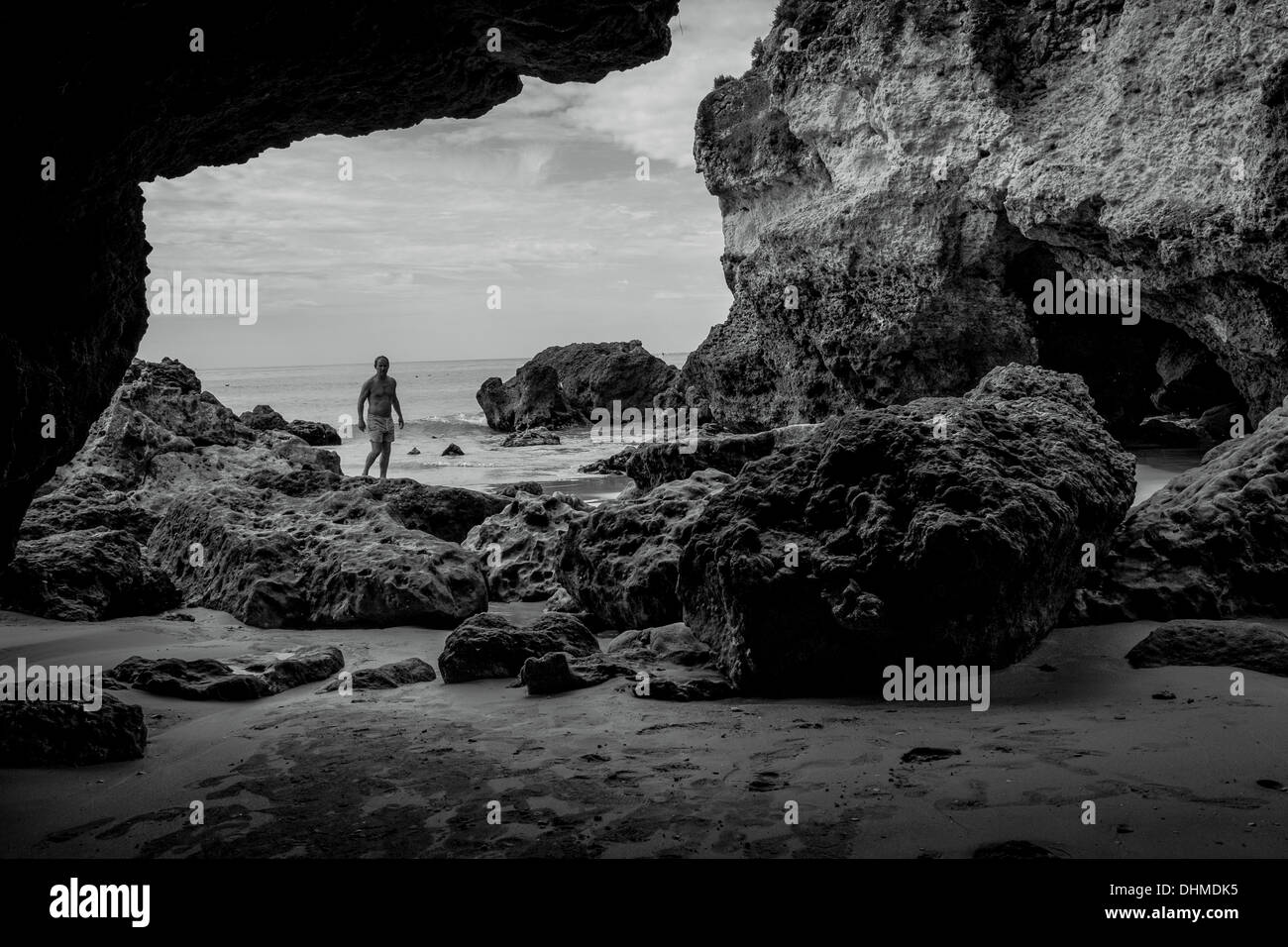 A man on the beach captured through a cave opening on the beach Praia ...