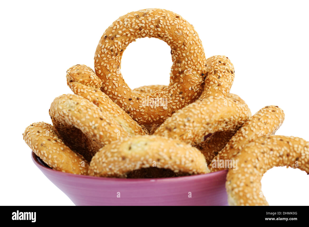 Round rusks with sesame seeds in pink bowl isolated on white background ...
