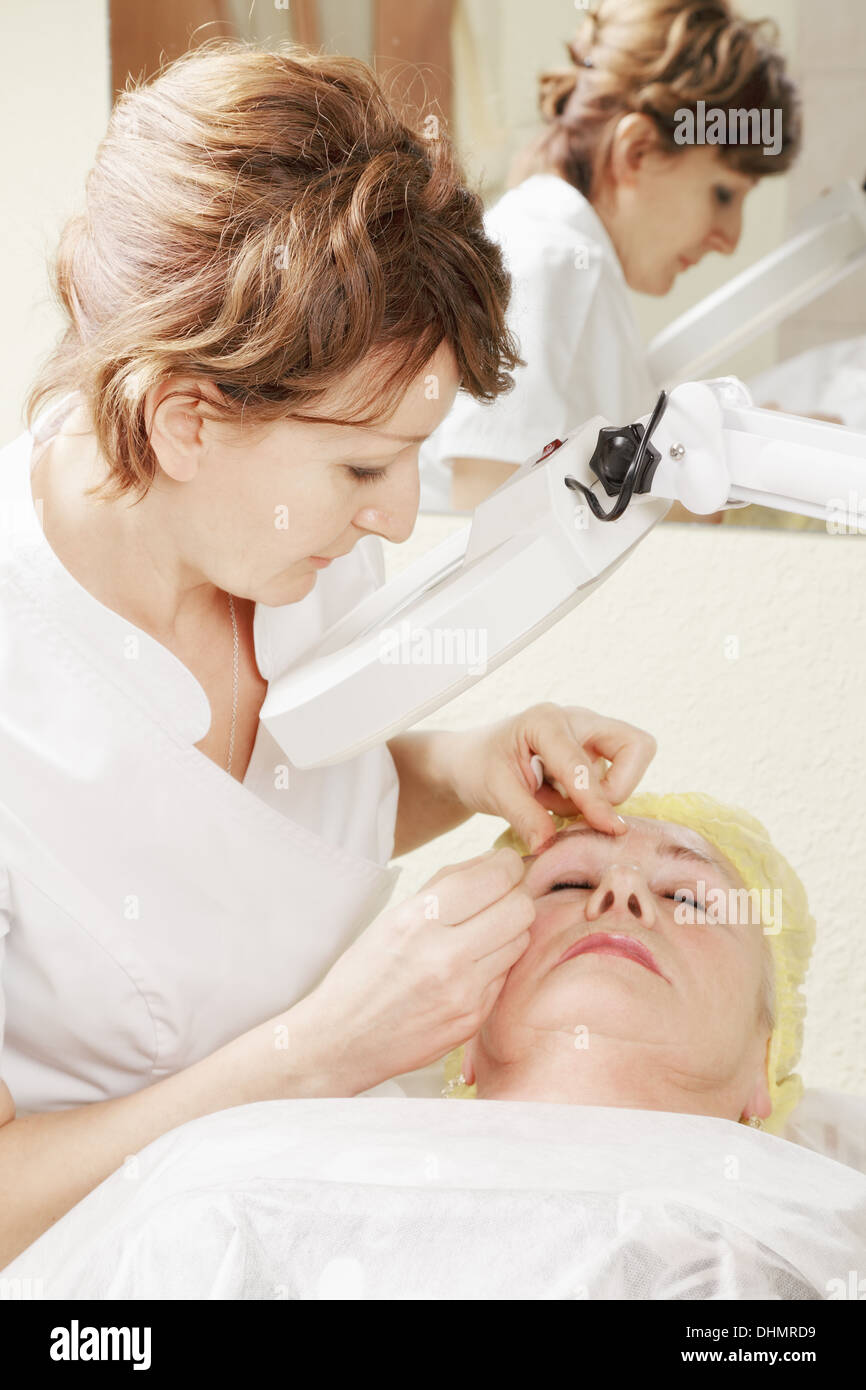 Beautician does eyebrows tweezing procedure Stock Photo - Alamy