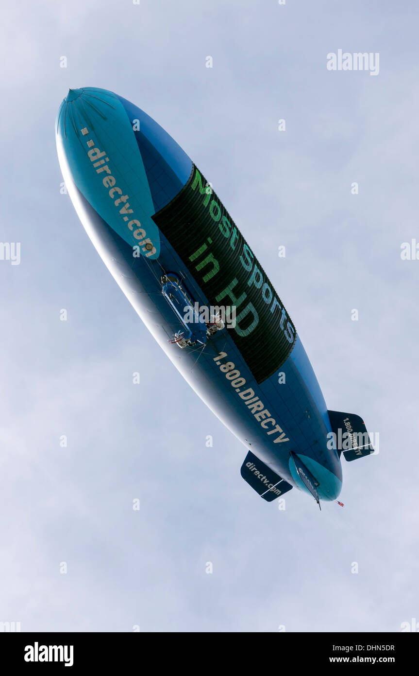 Blue and turquoise blimp navigates above football stadium advertising ...