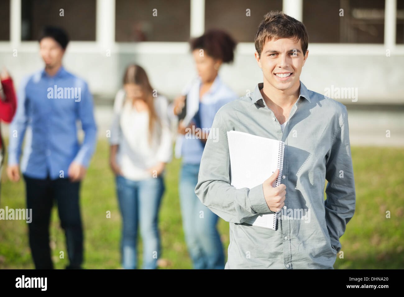 Man Holding Books With Students In Background On Campus Stock Photo - Alamy
