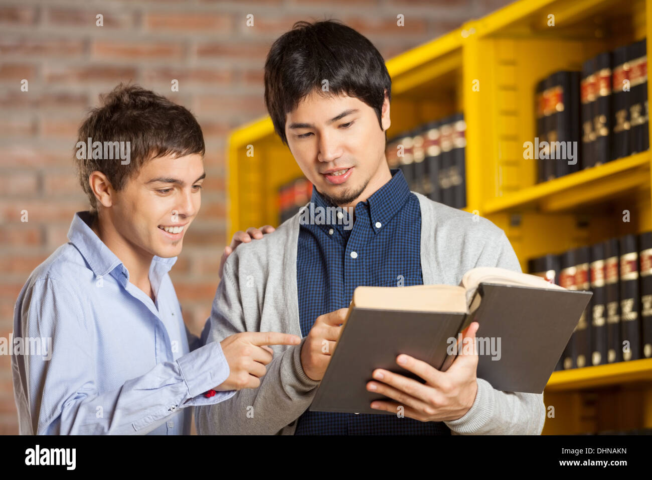 Friends Reading Book In College Library Stock Photo - Alamy