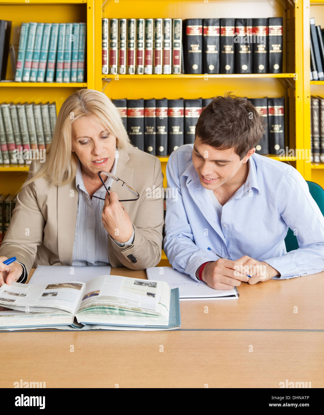 Teacher And Student Looking At Book While Sitting In Library Stock ...