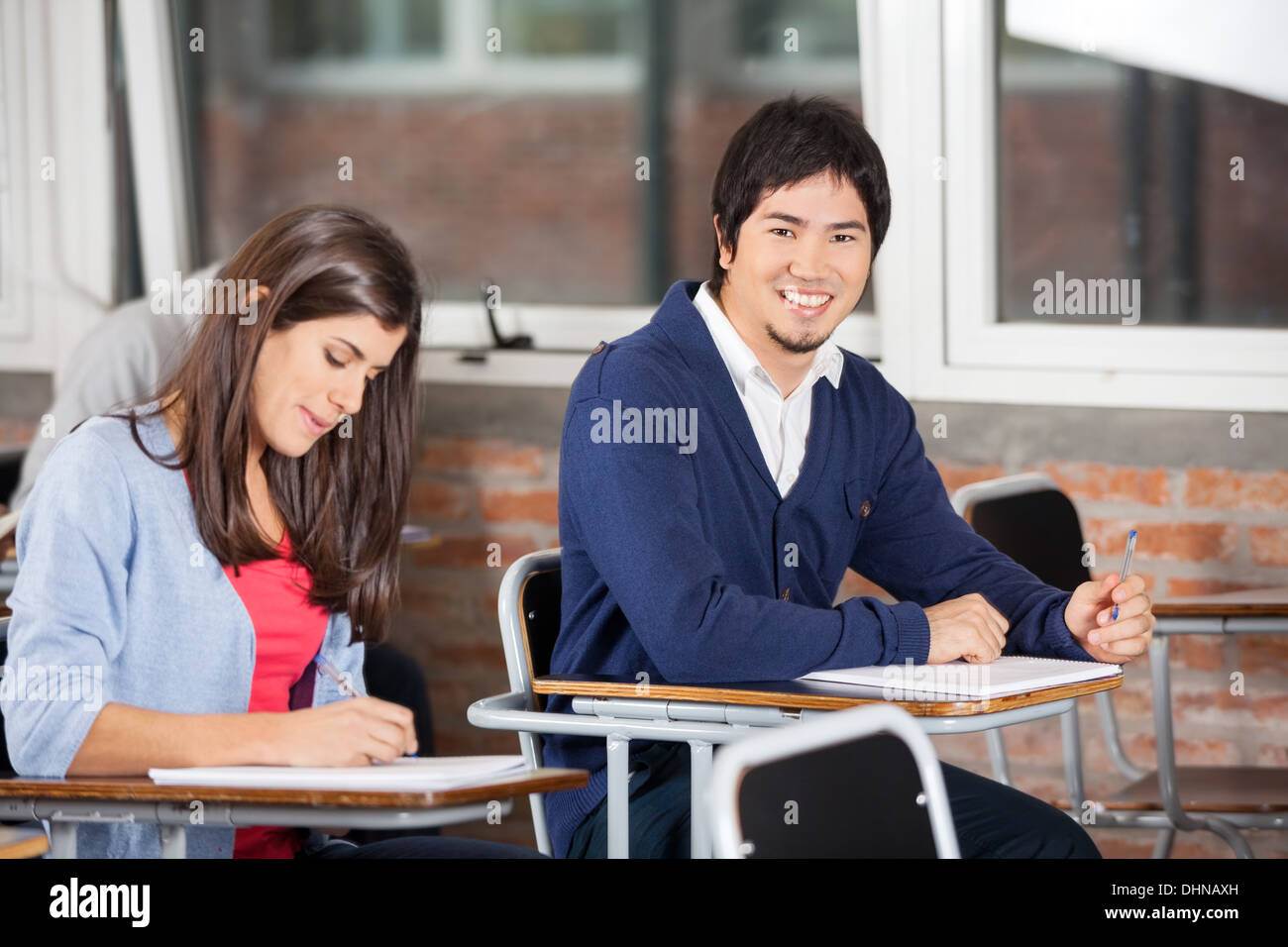 Student Sitting At Desk With Classmate In Classroom Stock Photo - Alamy