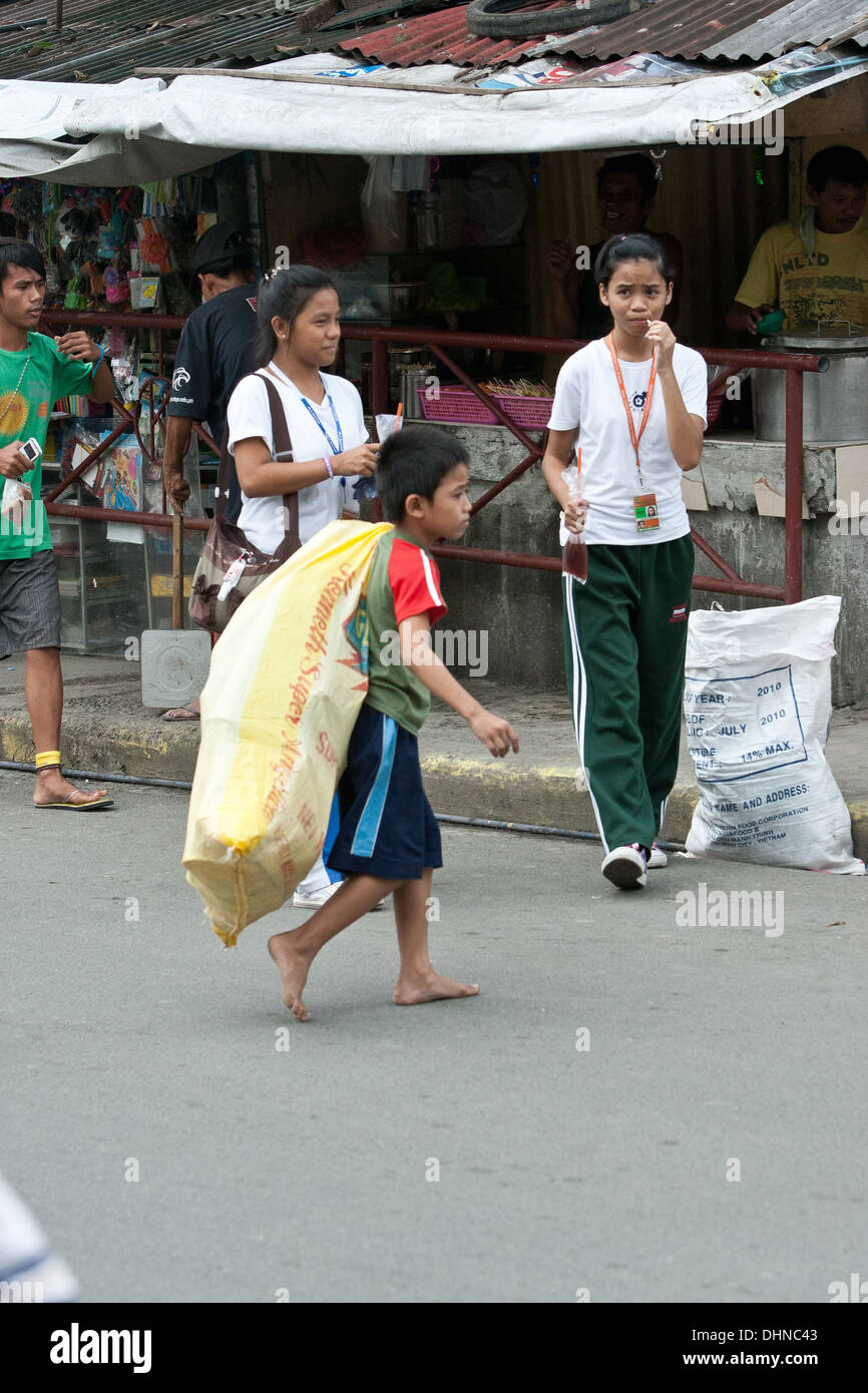 A young boy carries a load on his shoulder in the streets of ...