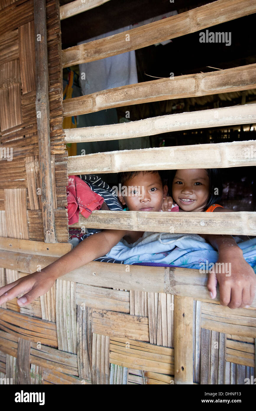 Two young local children smile out from the window of their home in ...