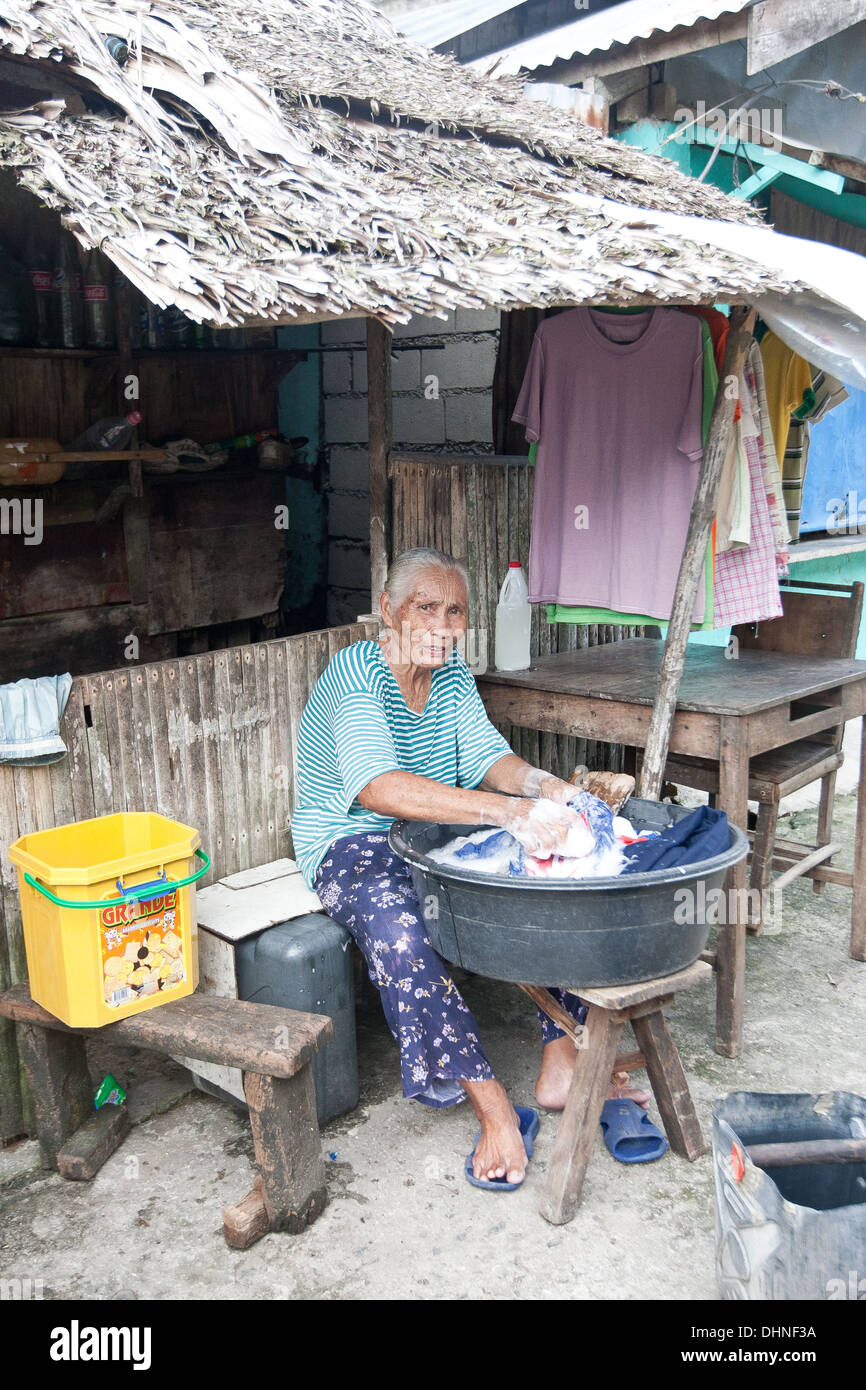 An elderly woman washes her clothes outdoors on the island of Samar ...