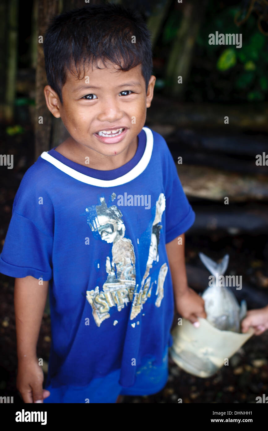 A young boy smiles as he carries a precious fish in his bucket on the ...