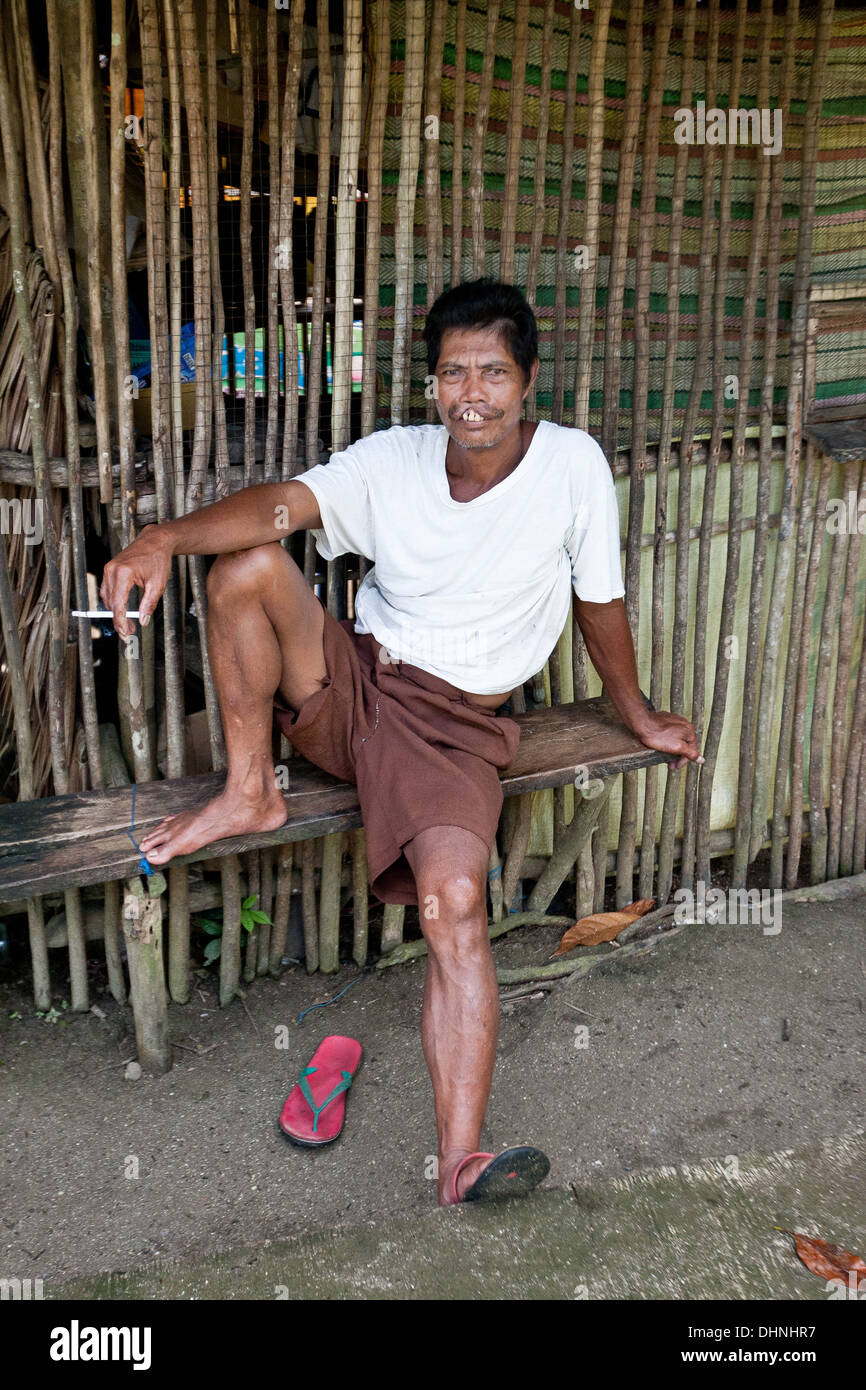A local man sits on a bench outside his house on the island of Samar ...
