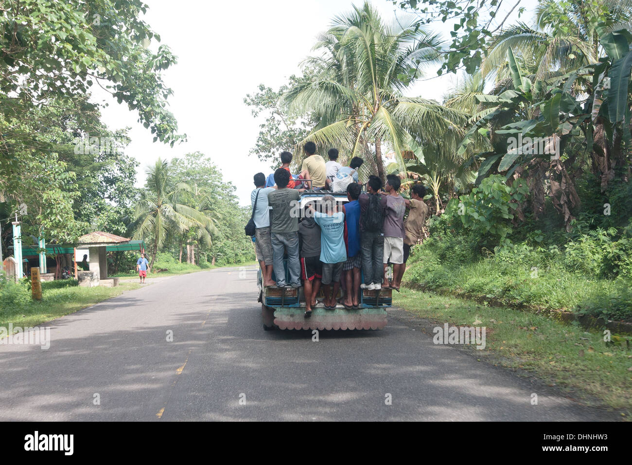 Passengers hold on tight as a loaded jeepney makes its way along a road ...