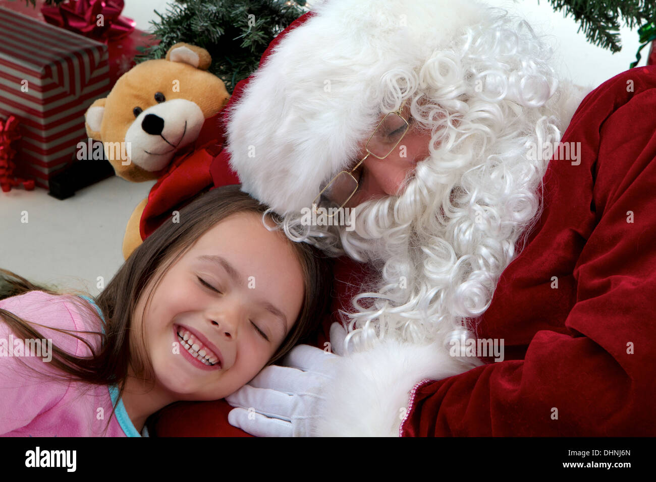 Santa and little girl fall asleep under the Christmas tree surrounded ...