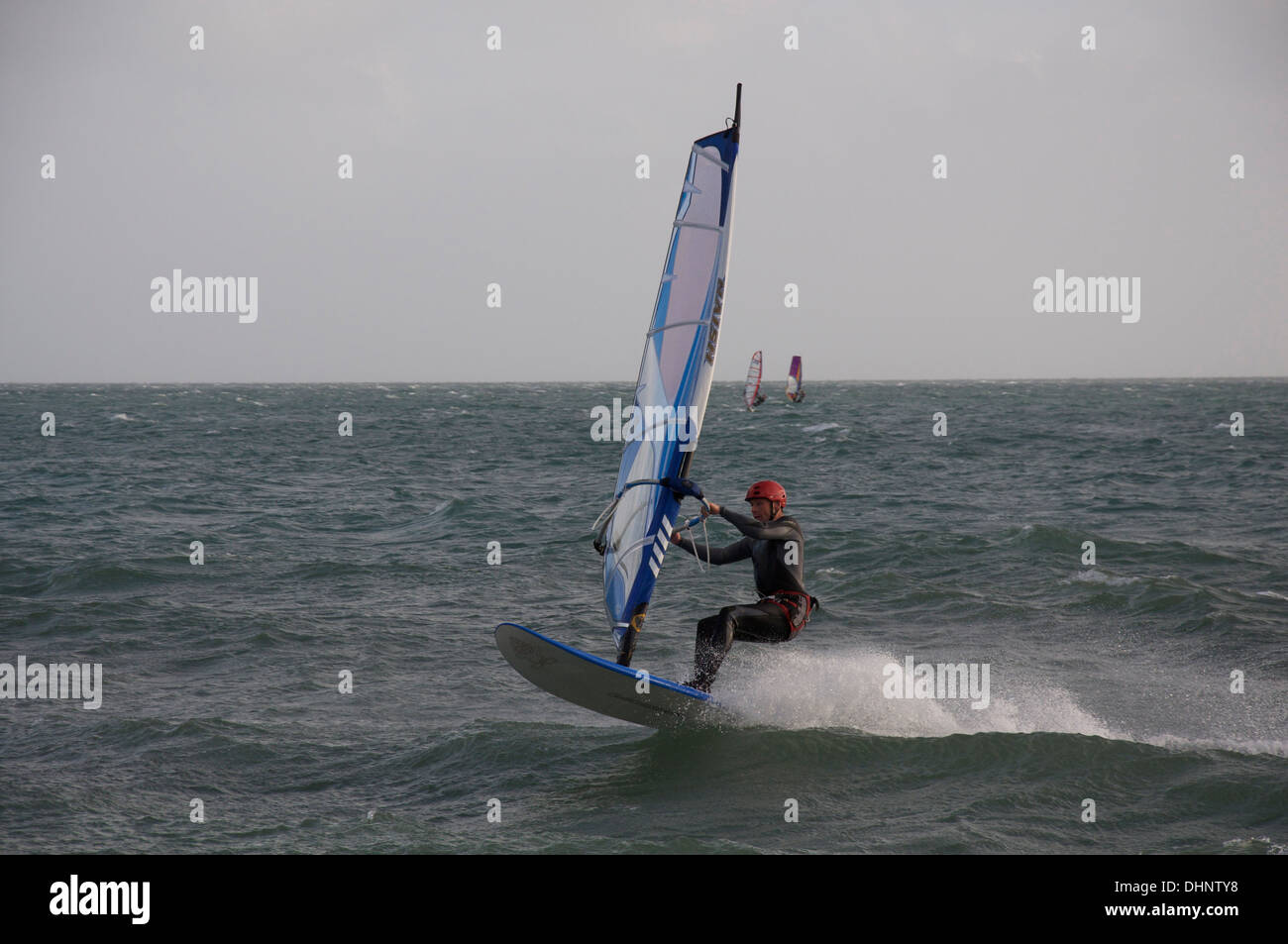 Water sports. Windsurfing man, wearing a wetsuit, speeding over the ...