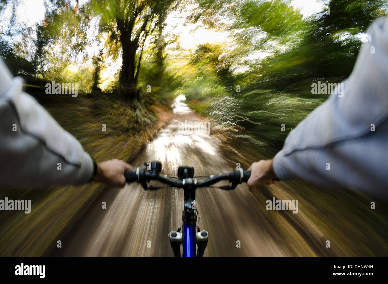 View over the handle bars along tree lined muddy bridal path country ...
