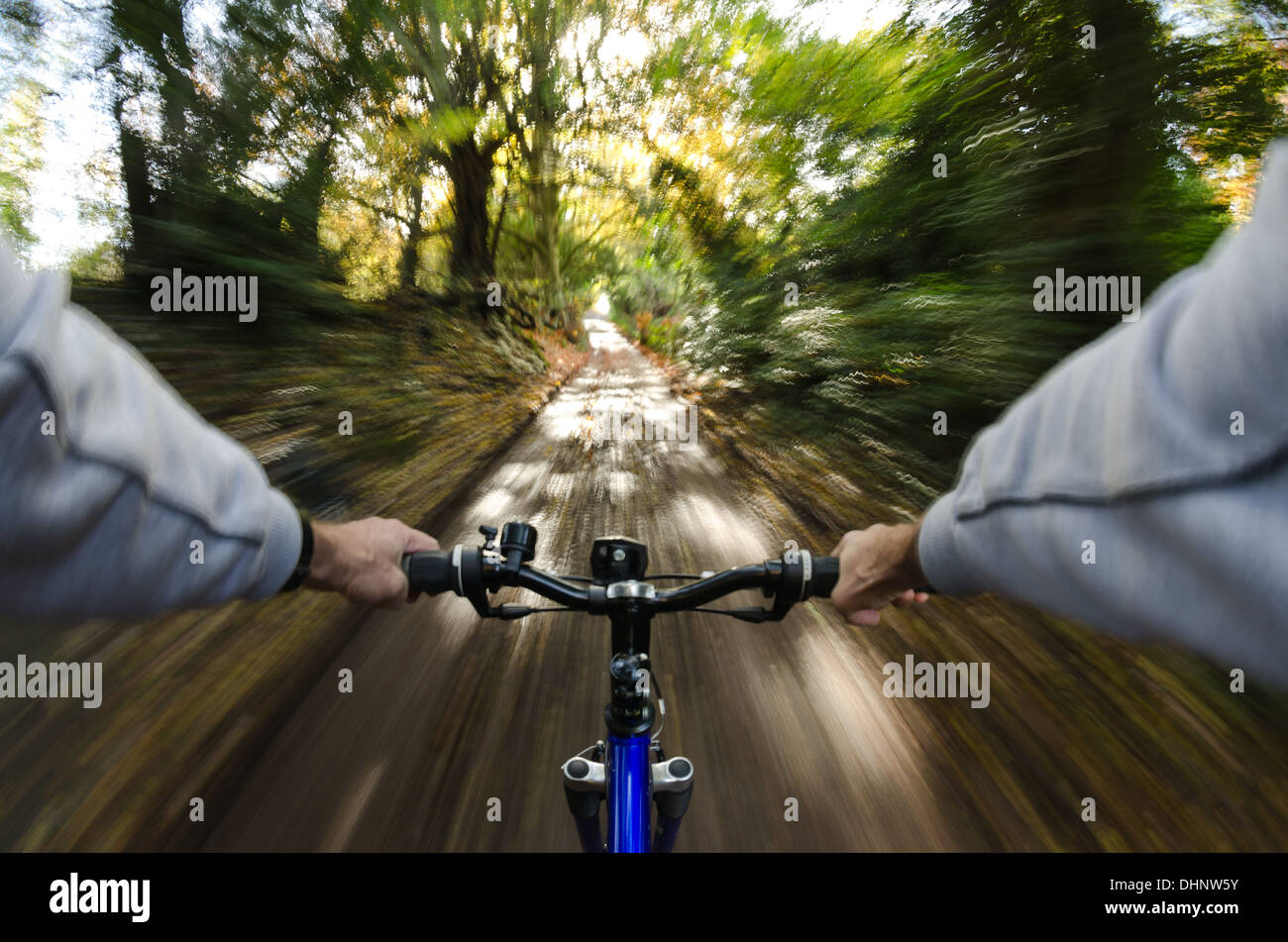 View over the handle bars along tree lined muddy bridal path country ...