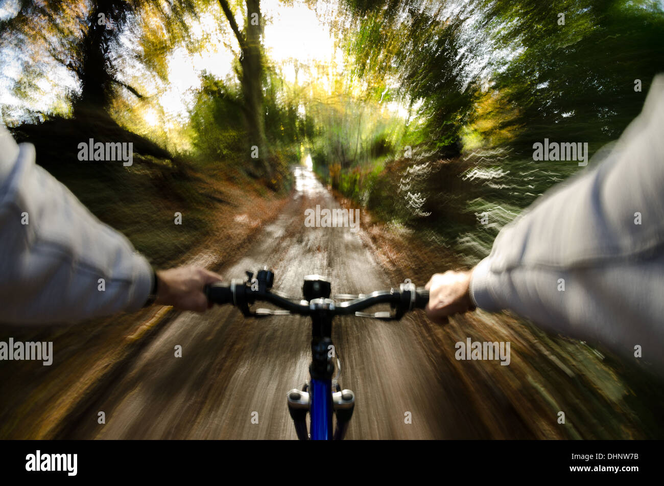View over the handle bars along tree lined muddy bridal path country ...