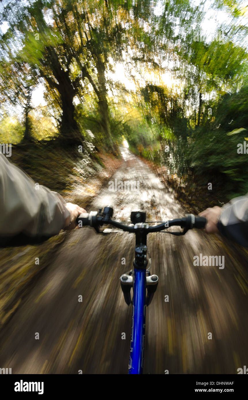 View over the handle bars along tree lined muddy bridal path country ...