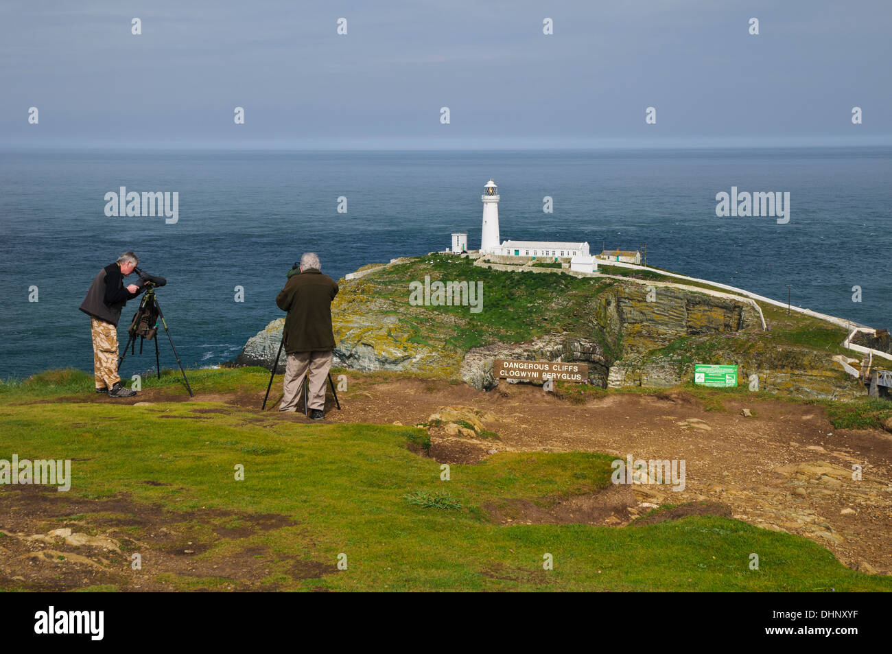 Two bird watchers using spotting scopes to view the nesting seabirds on ...