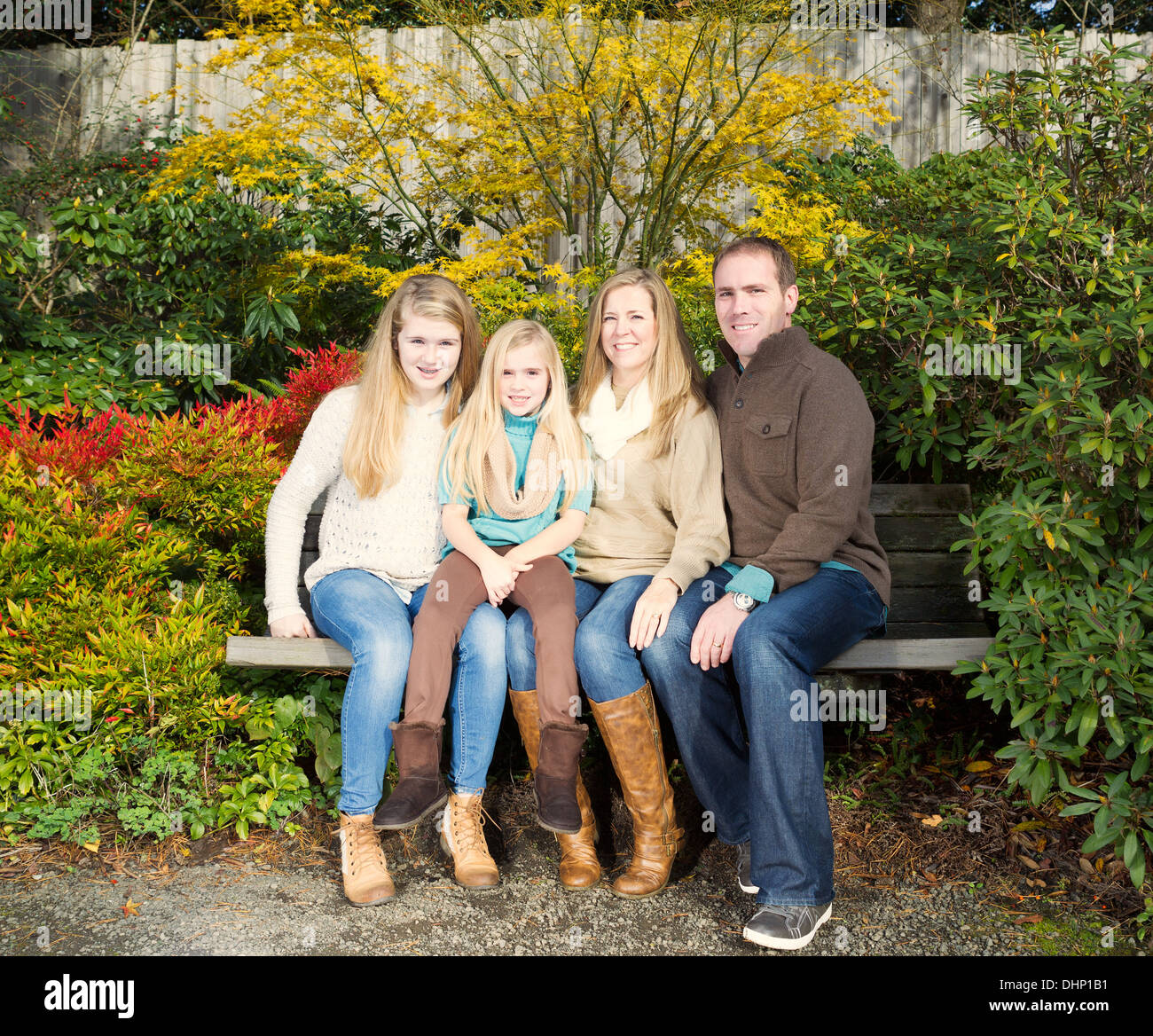 Photo of family all sitting on park bench during a nice day in the fall ...