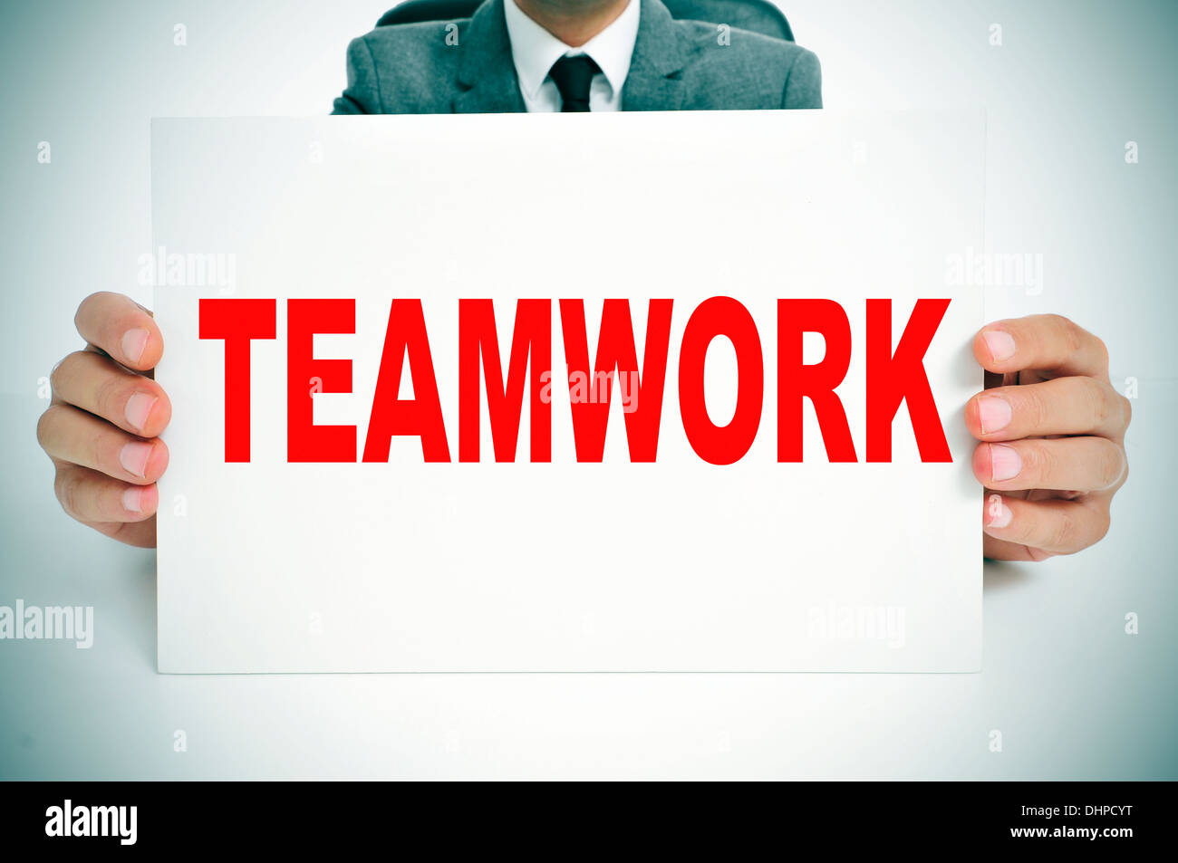 a man wearing a suit sitting in a desk holding a signboard with the ...