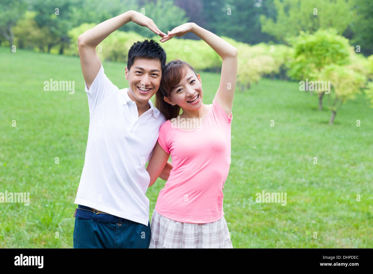 Sweet young couple making heart shape with arms Stock Photo - Alamy