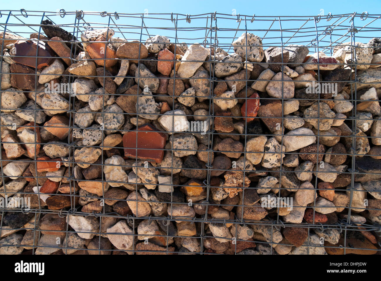 Rubble wall made from industrial site waste, contained within wire cage ...