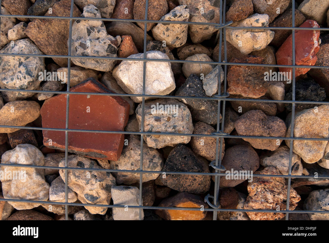 Rubble wall made from industrial site waste, contained within wire cage ...