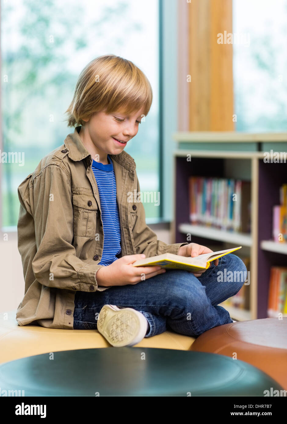 Happy Boy Reading Book In Library Stock Photo - Alamy