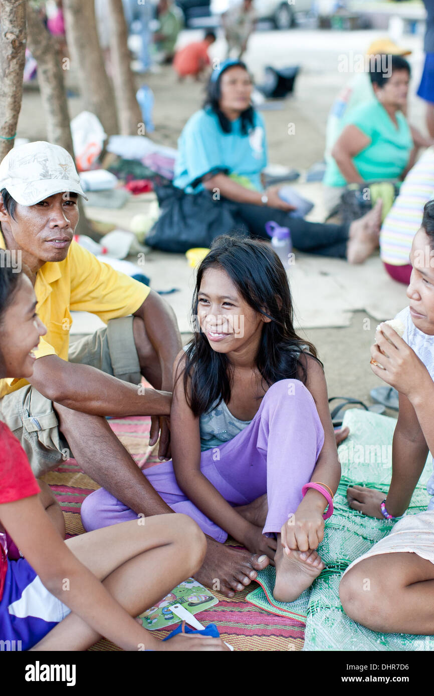 Families in the homeless community sit together on makeshift mats by ...
