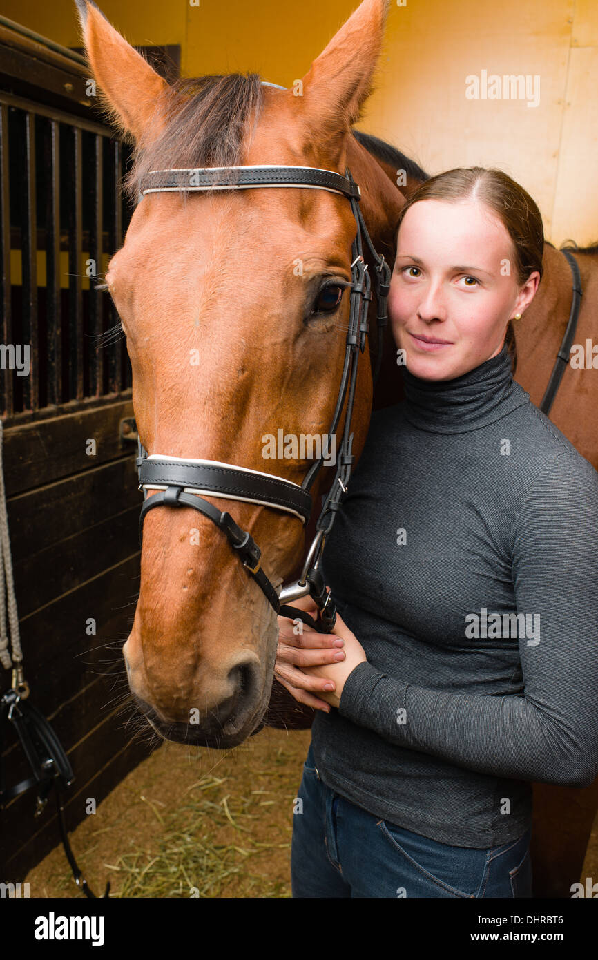 Woman bridle a horse in the stall Stock Photo - Alamy