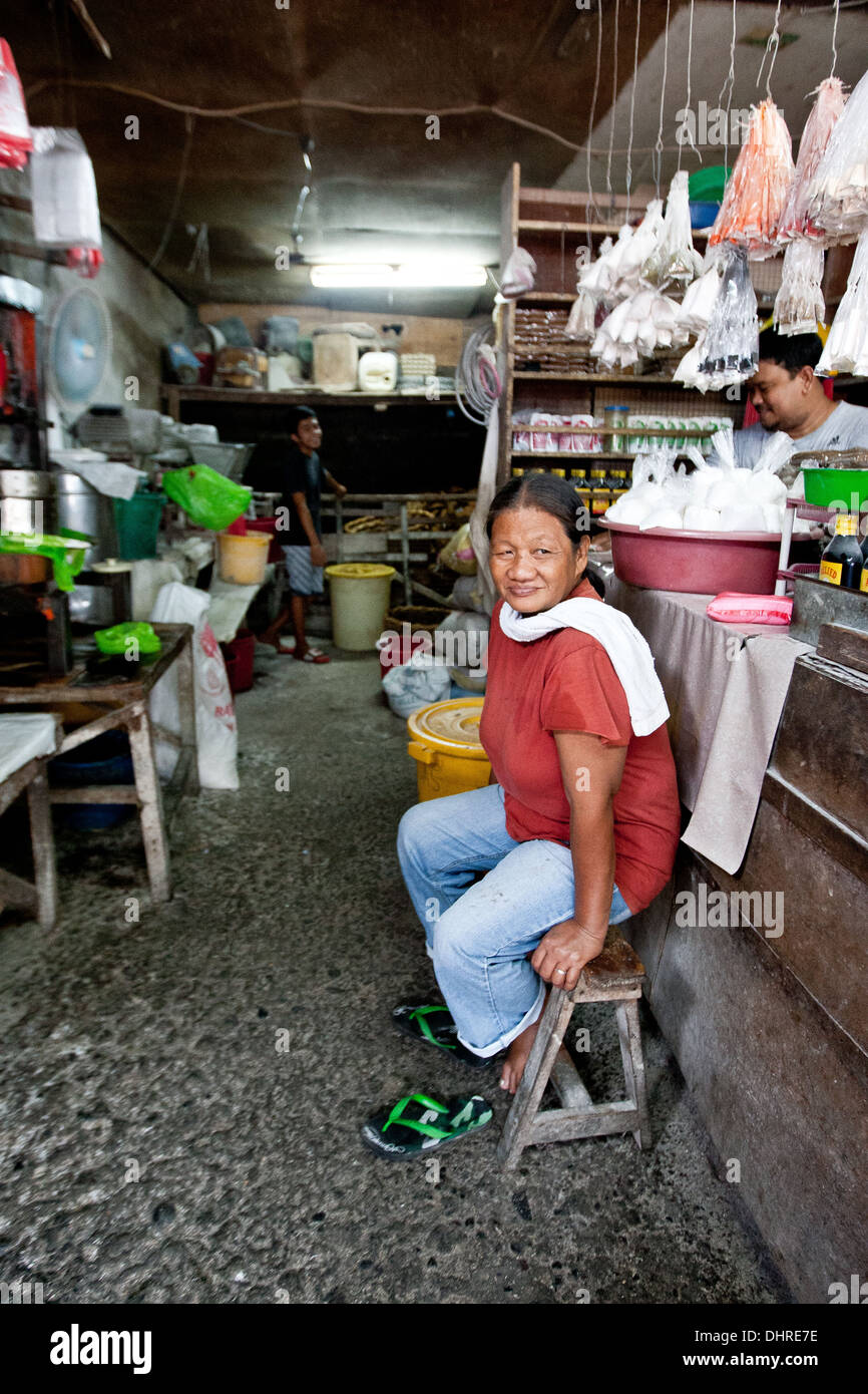 A woman sits beside her family's market stall in Davao Stock Photo - Alamy