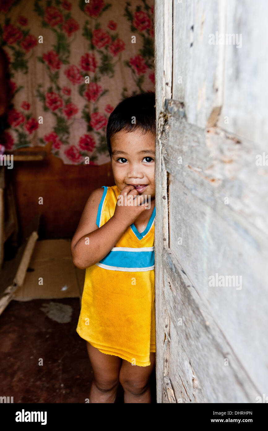 A little boy smiles shyly from the doorway of his village home in the ...
