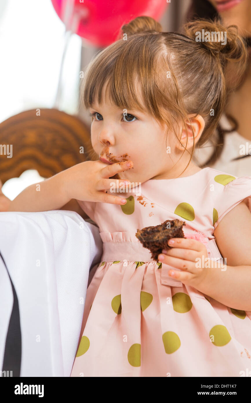 Cute Girl Eating Cake With Icing On Her Face Stock Photo - Alamy