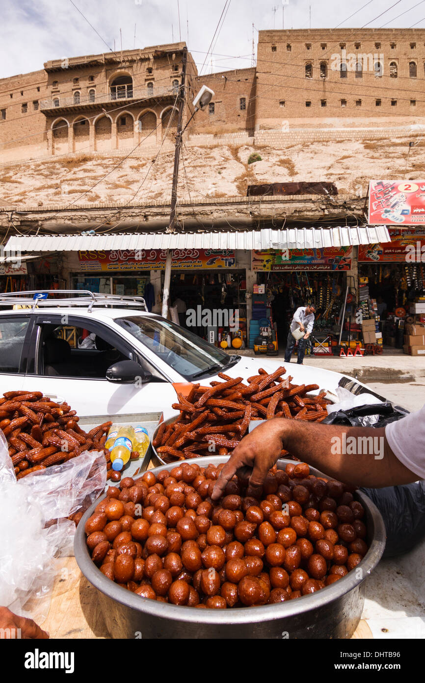 Sweets sold in a street market with citadel in background. Erbil, Iraq ...