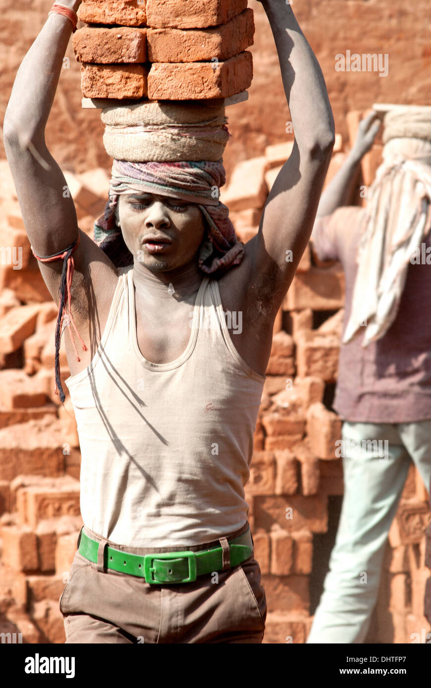 Worker carrying bricks in his head Stock Photo - Alamy