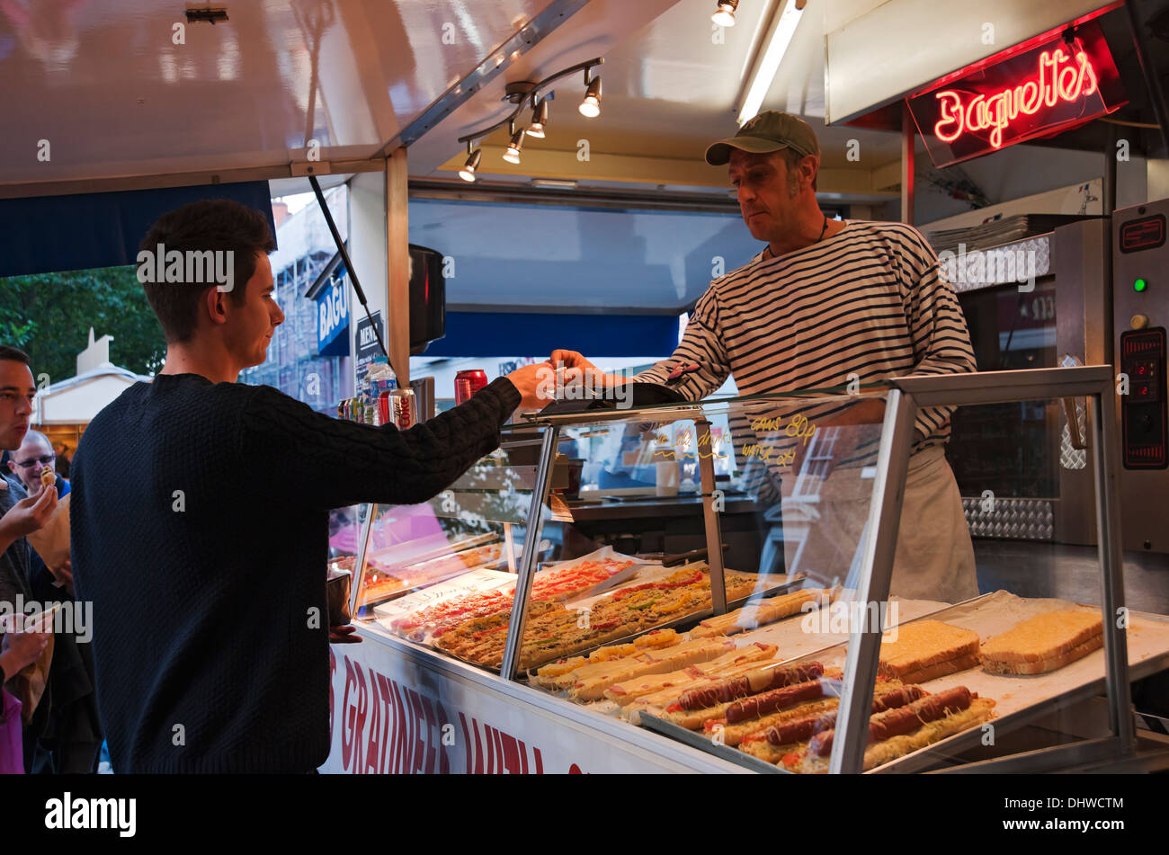 Vendor man person selling serving filled baguettes sandwiches on food ...