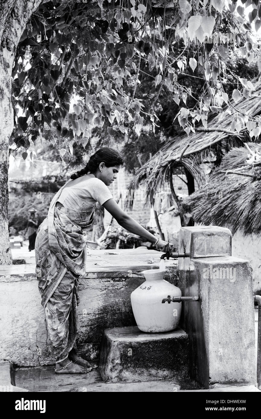 Indian woman filling a plastic pot with water from a standpipe in a ...