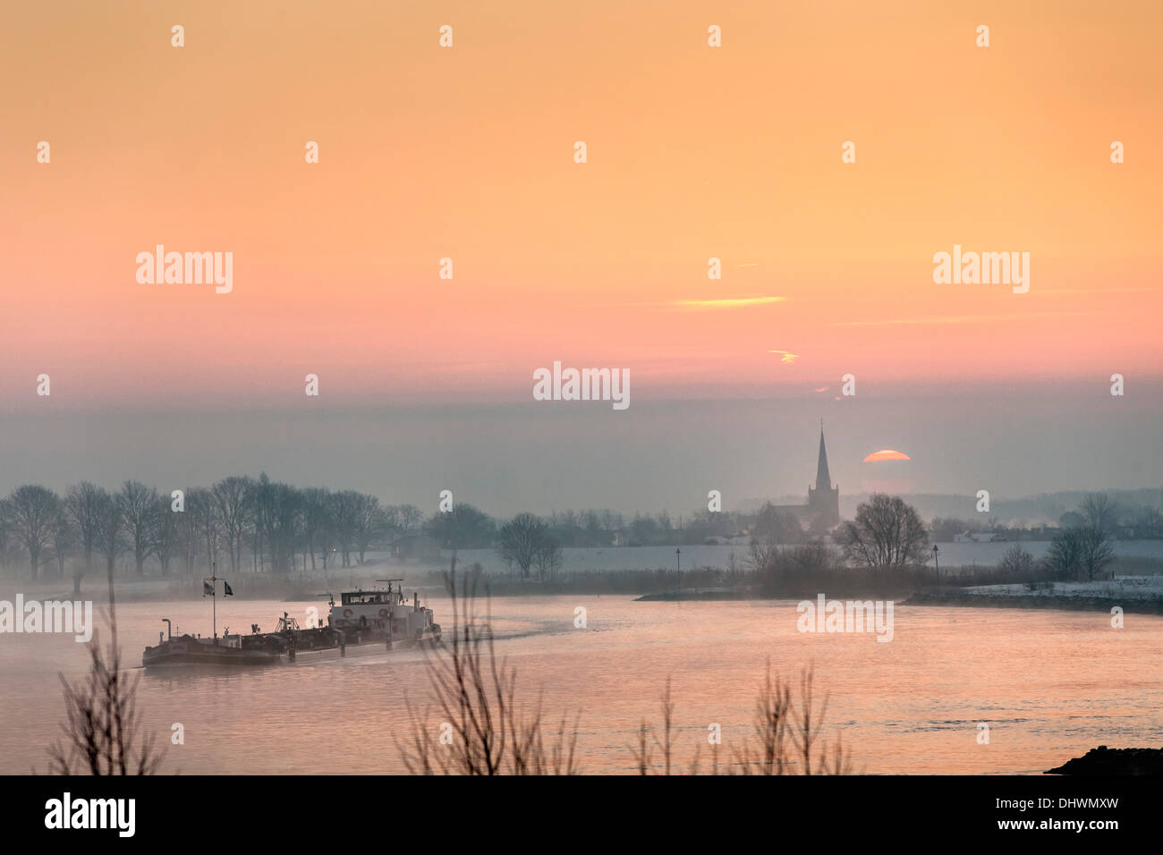 Netherlands, Lopik, Skyline of village near Lek river. Inland barge ...