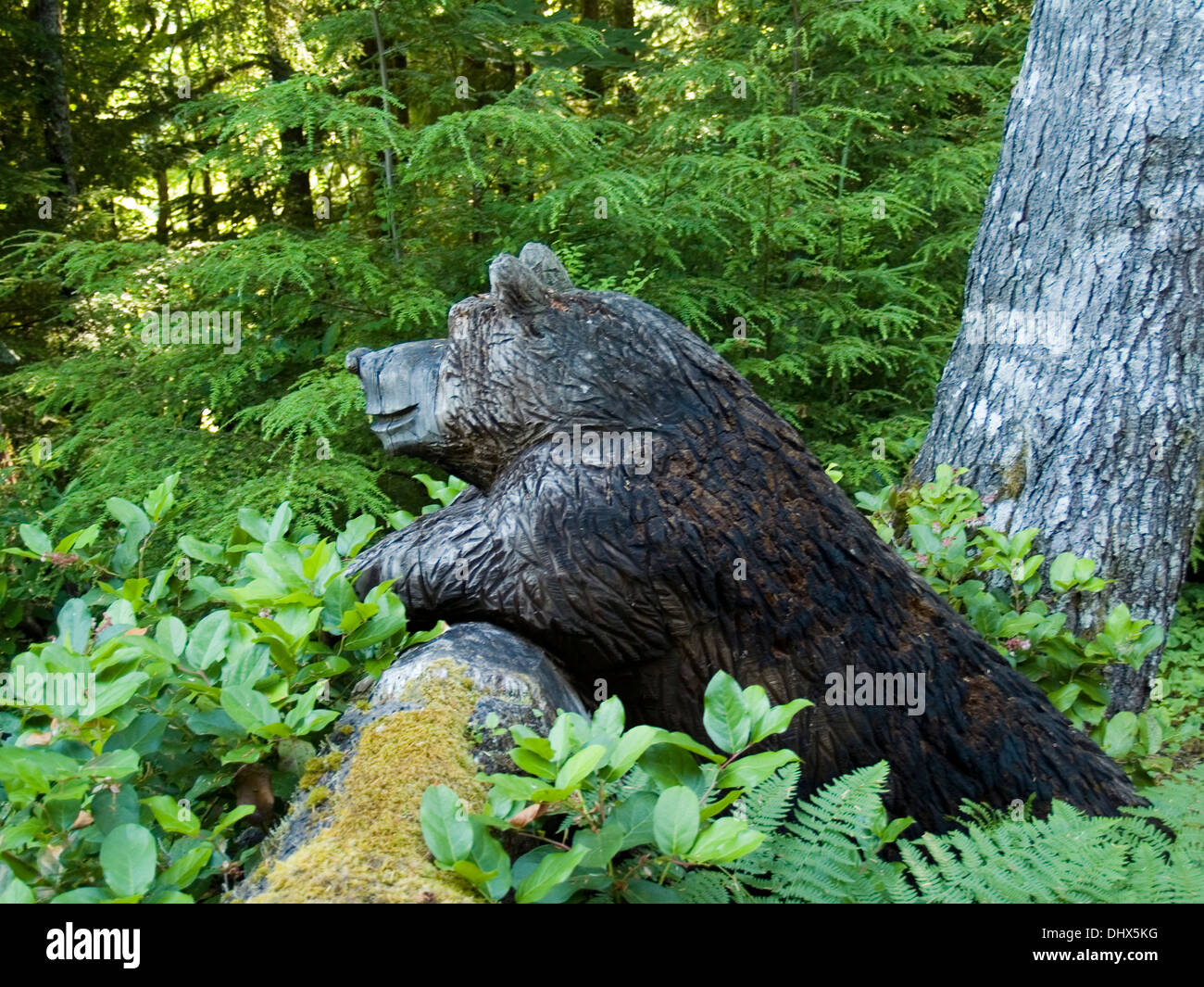 Carved bear leaning on a log,Washington State Stock Photo - Alamy