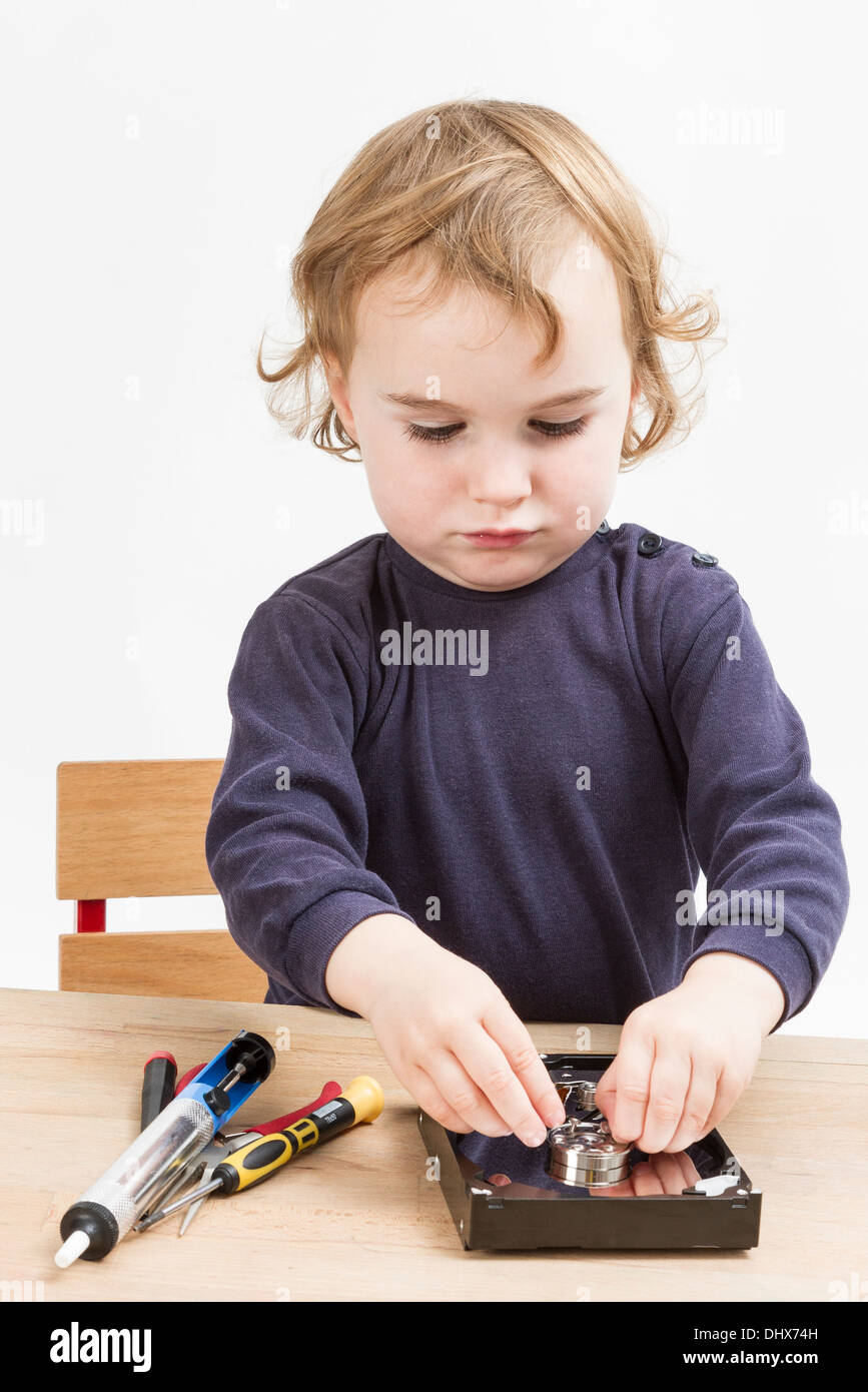 little girl repairing computer parts. studio shot with neutral grey ...