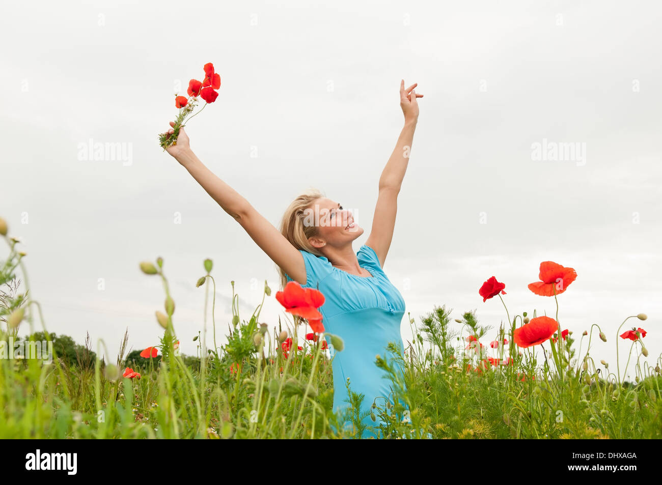 pretty young blond woman cheering in the poppy fie Stock Photo - Alamy