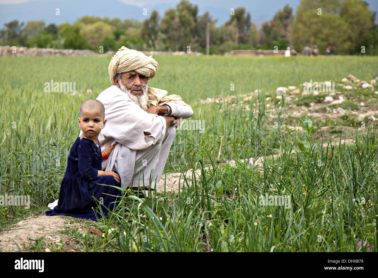 An Afghan elder and children watch a military patrol in a village April ...