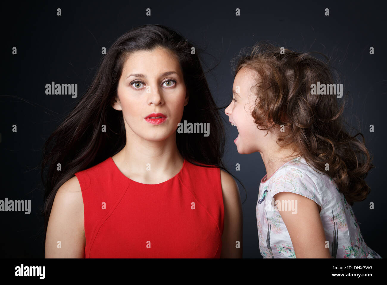 Mother listens as her girl shouts in her ear Stock Photo - Alamy