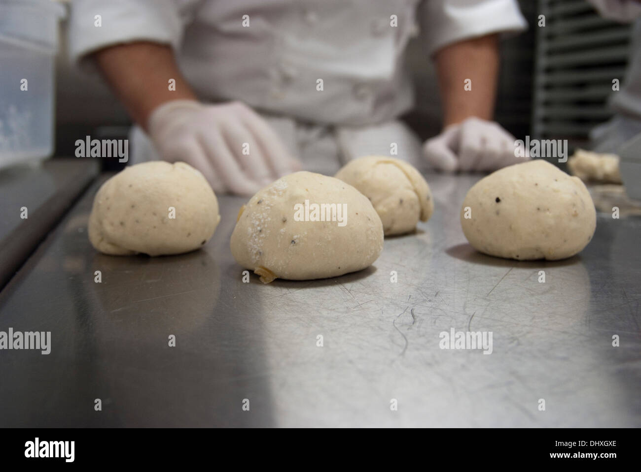 Trainee chef rolling bread dough into rolls in a commercial kitchen ...