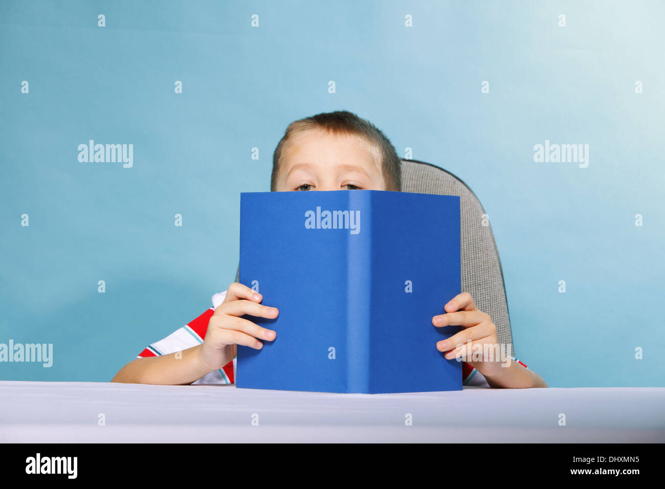 Young boy reading a book, child kid on blue background holding an open ...