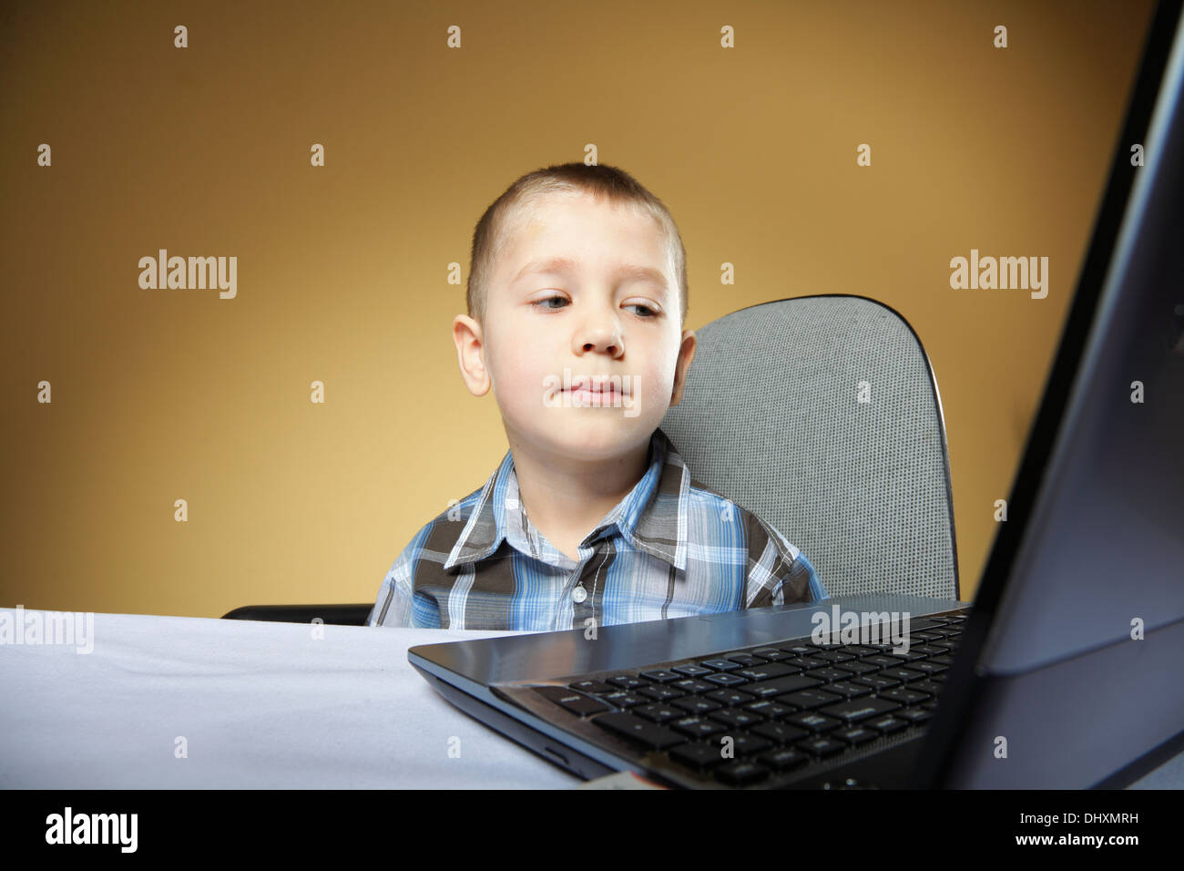 Computer addiction child boy with laptop notebook brown background ...